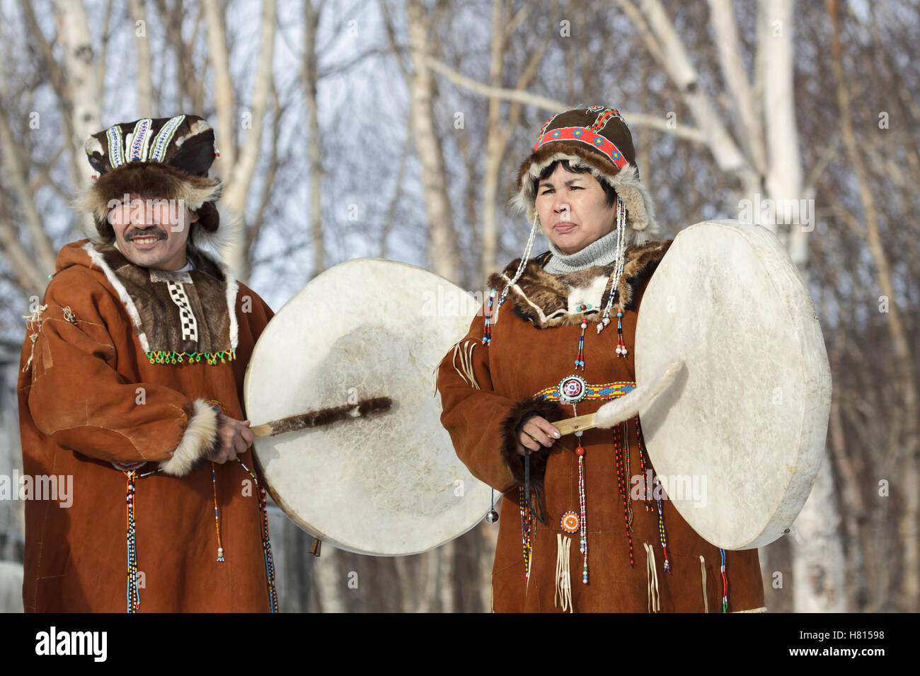 Man and woman in the Koryak national dress stand with tambourines in ...