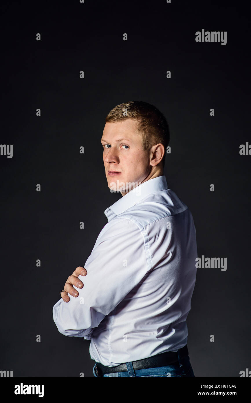 Serious man standing sides in a half-turn with folded hands. Studio ...