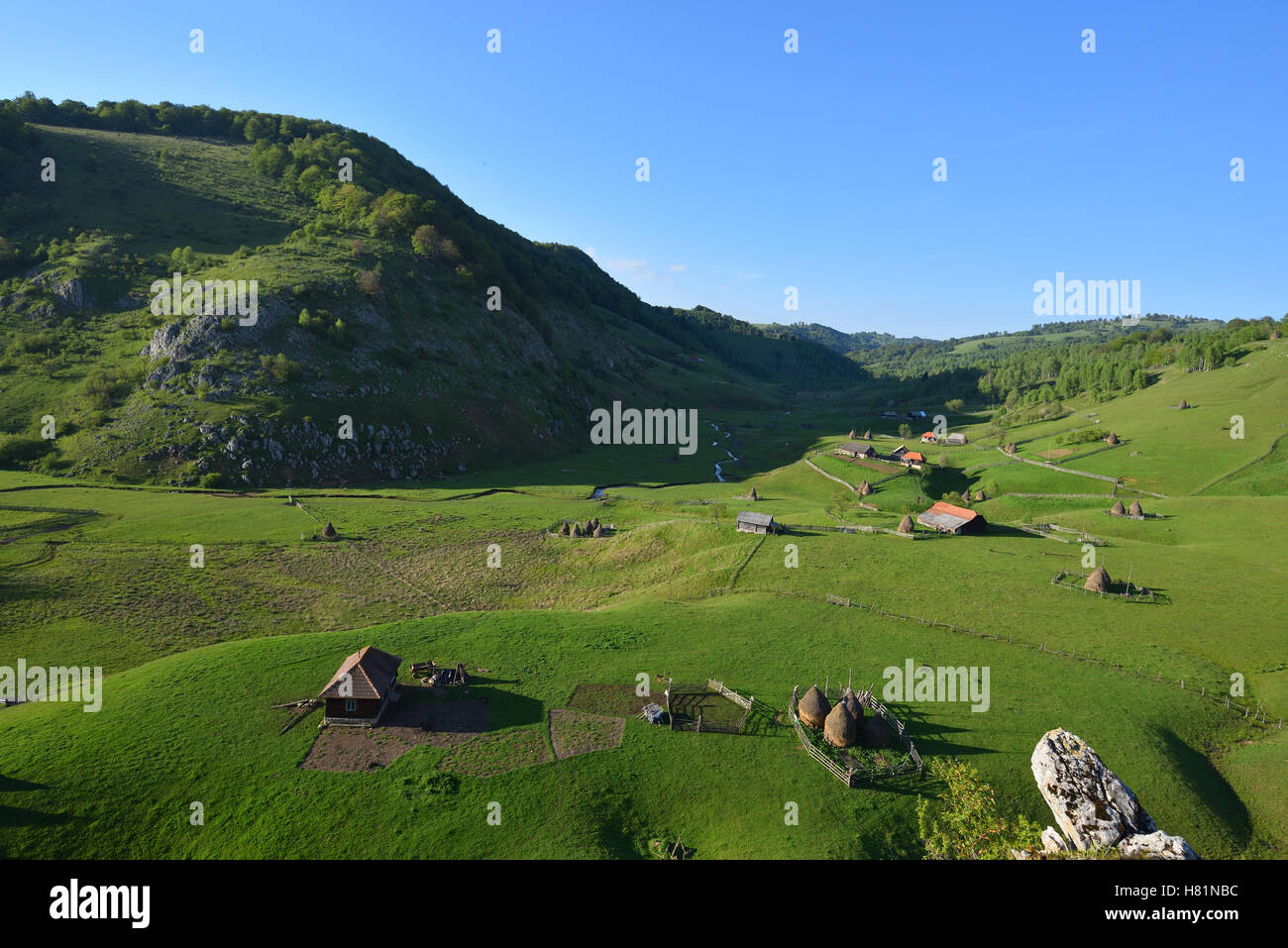 Rural mountain landscape with old house and haystacks against cloudy ...