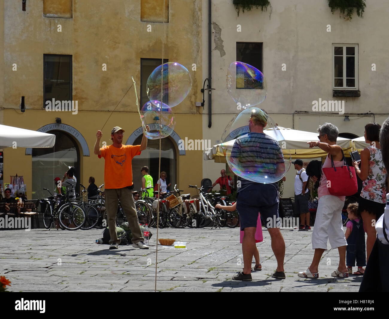 Street entertainer creating large bubbles to entertain a small crowd ...