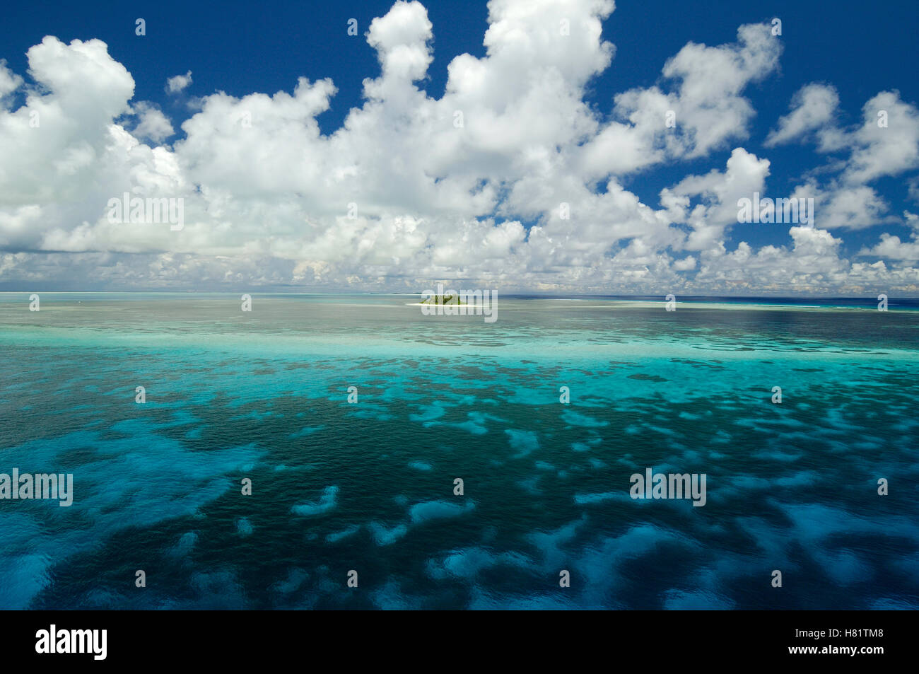 Clouds above sea and island with barrier reef, Bijoutier Island ...
