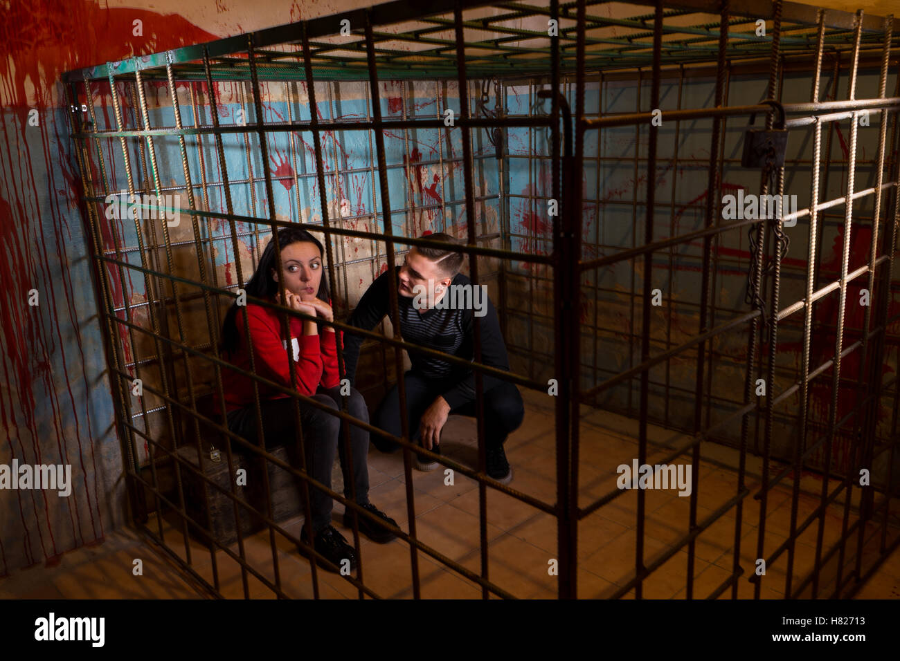Couple of frightened Halloween victims imprisoned in a metal cage with ...