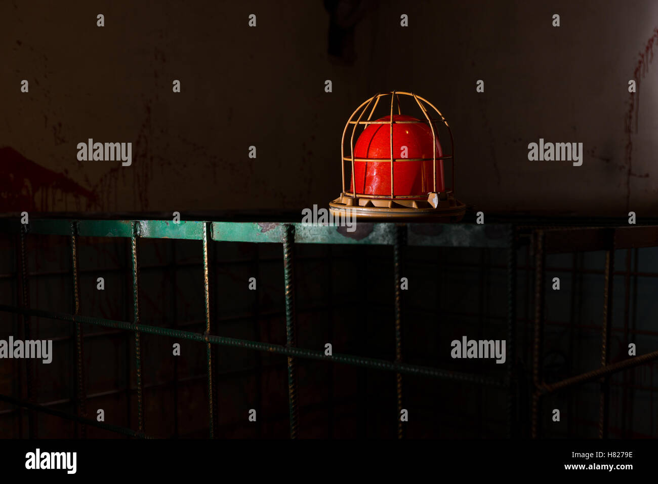 Red lamp on the iron cage behind blood splattered wall for concept ...