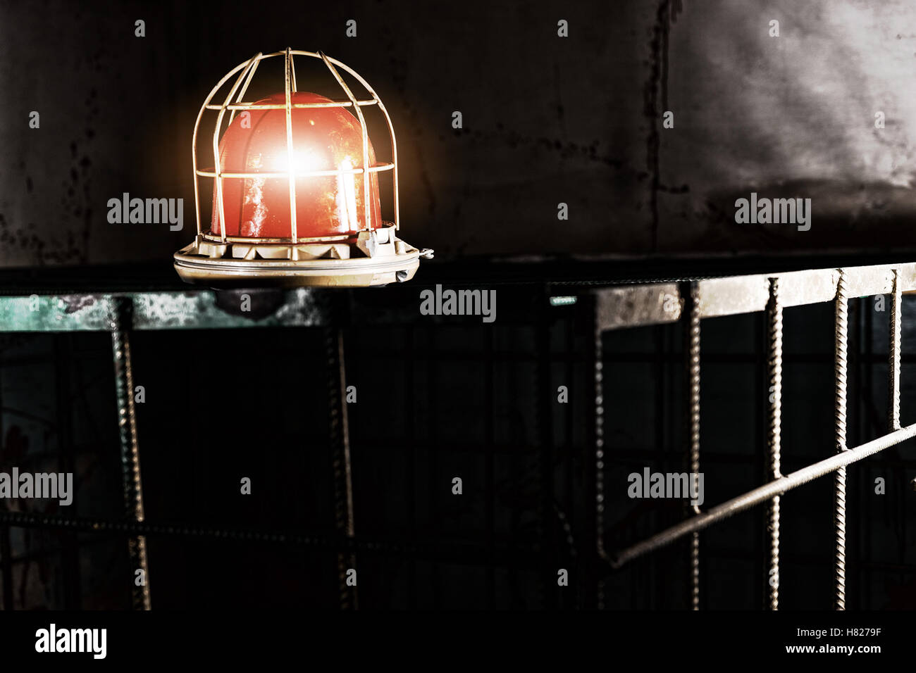 Shining red lamp on the iron cage behind blood splattered wall for ...