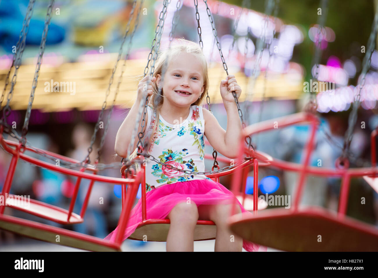 Cute little girl at fun fair, chain swing ride Stock Photo - Alamy