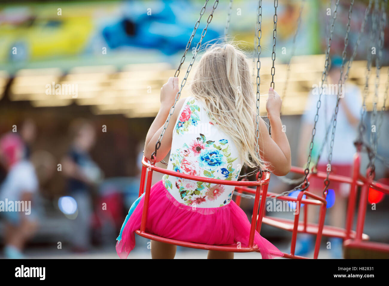 Cute little girl at fun fair, chain swing ride Stock Photo - Alamy