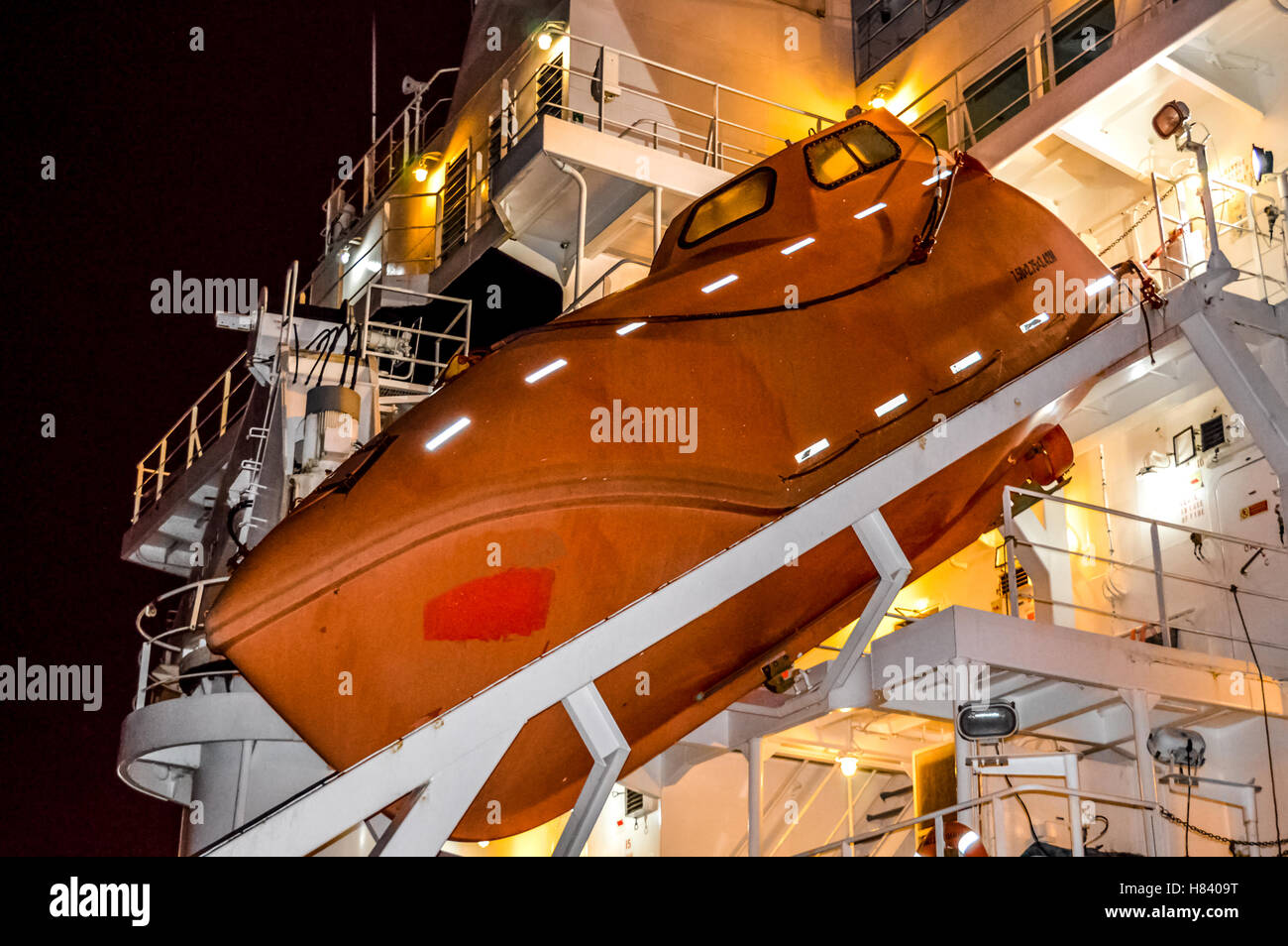 Orange life boats on a cruiseship docked at port waiting for passengers ...