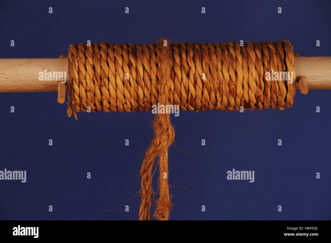 Rough hessian rope wound on a spindle isolated on a blue background ...