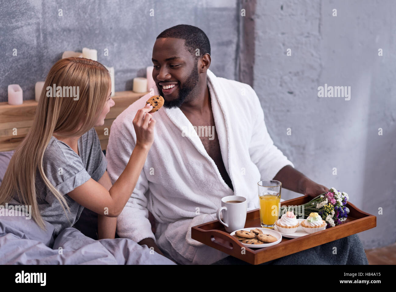 Delighted couple feeding each other in their bedroom Stock Photo - Alamy