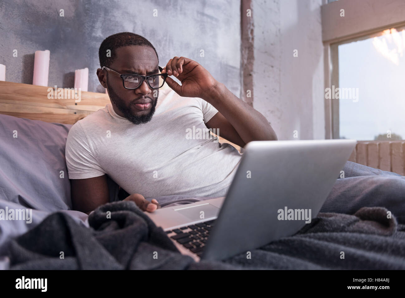 African man using laptop in bedroom Stock Photo - Alamy