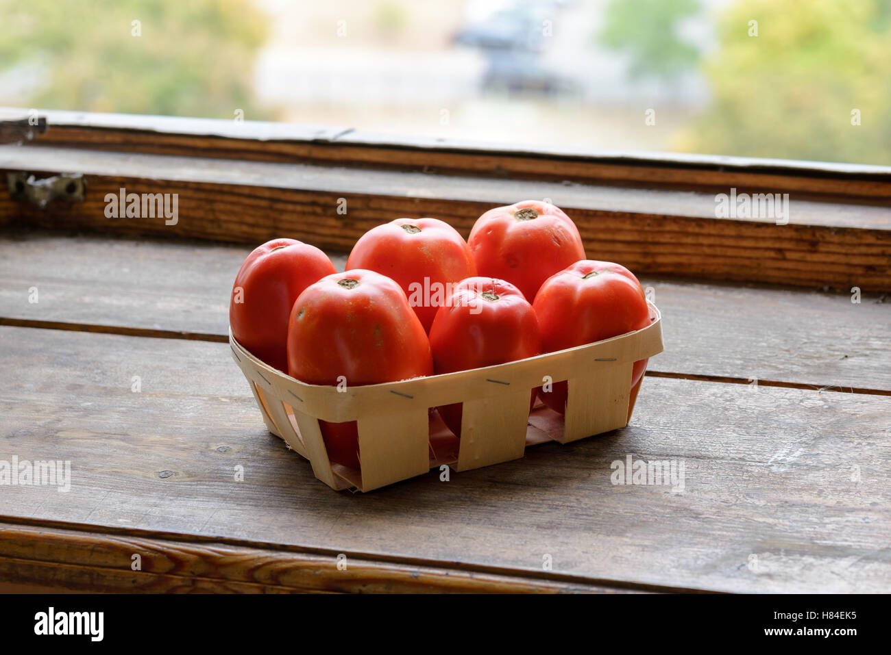 Six red natural tomatoes in a little crate close to the window Stock ...