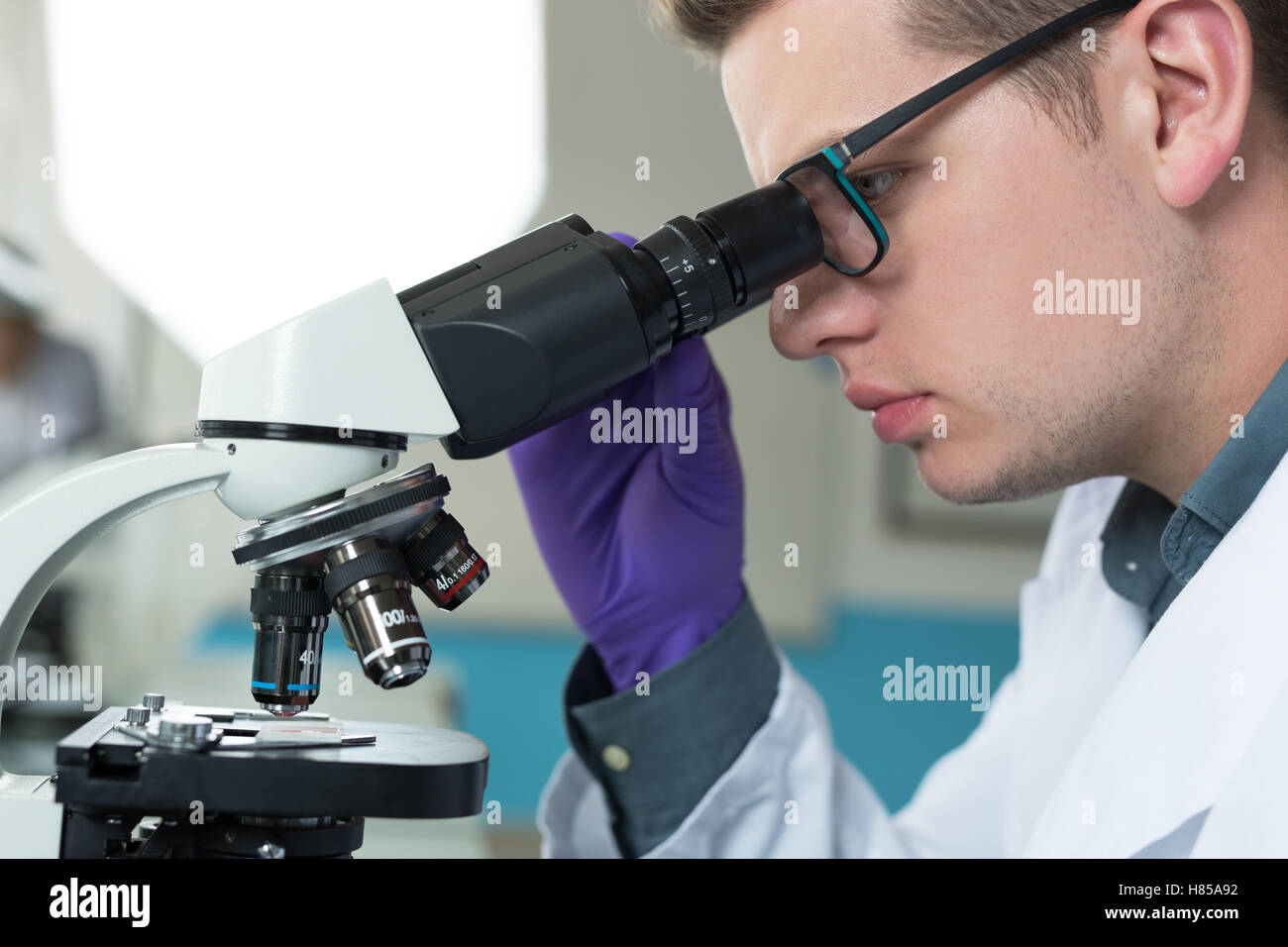 Young scientist investigating microbiological substance in microscope ...