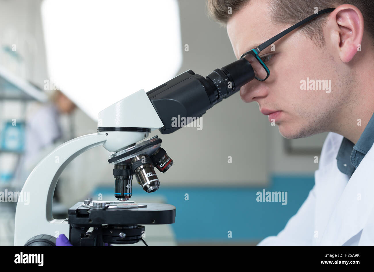 Young scientist investigating microbiological substance in microscope ...
