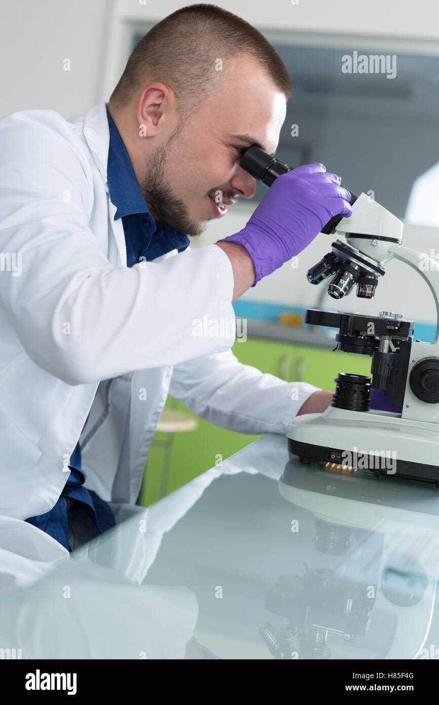 Young scientist investigating microbiological substance in microscope ...