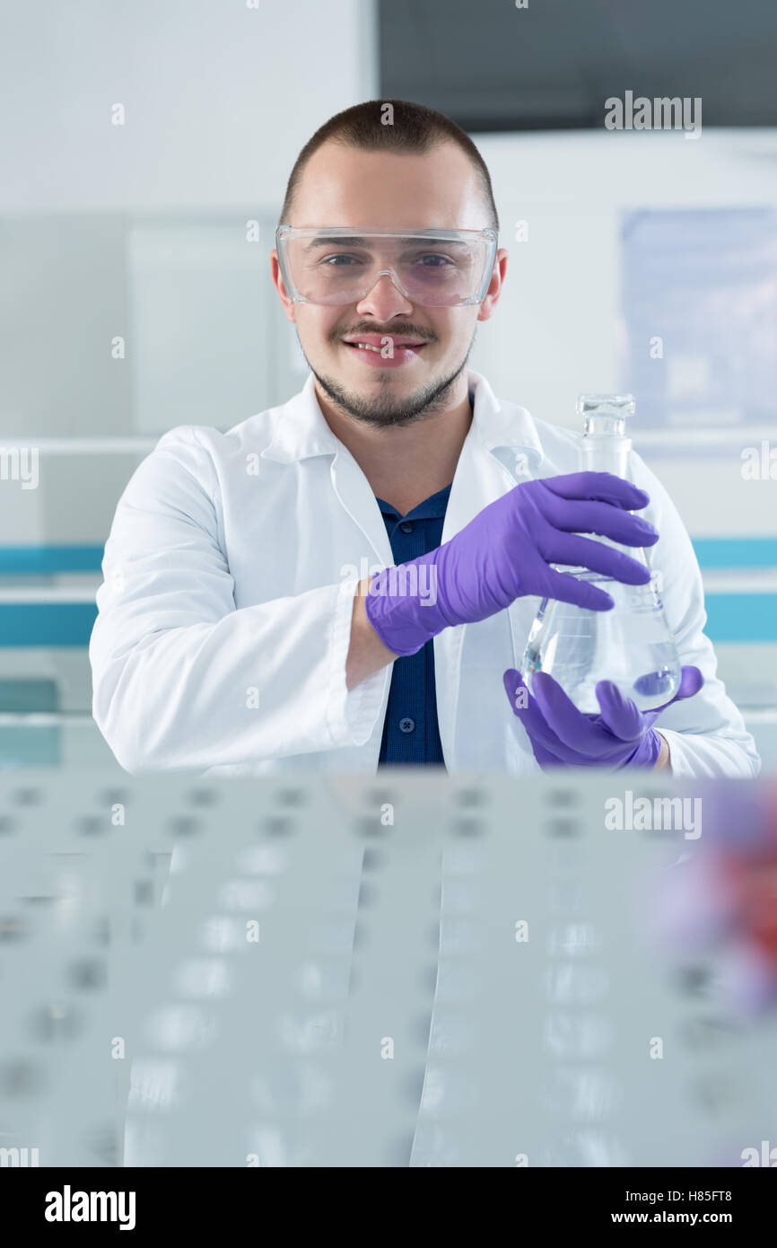Modern chemist looking at liquid in flask in laboratory Stock Photo - Alamy
