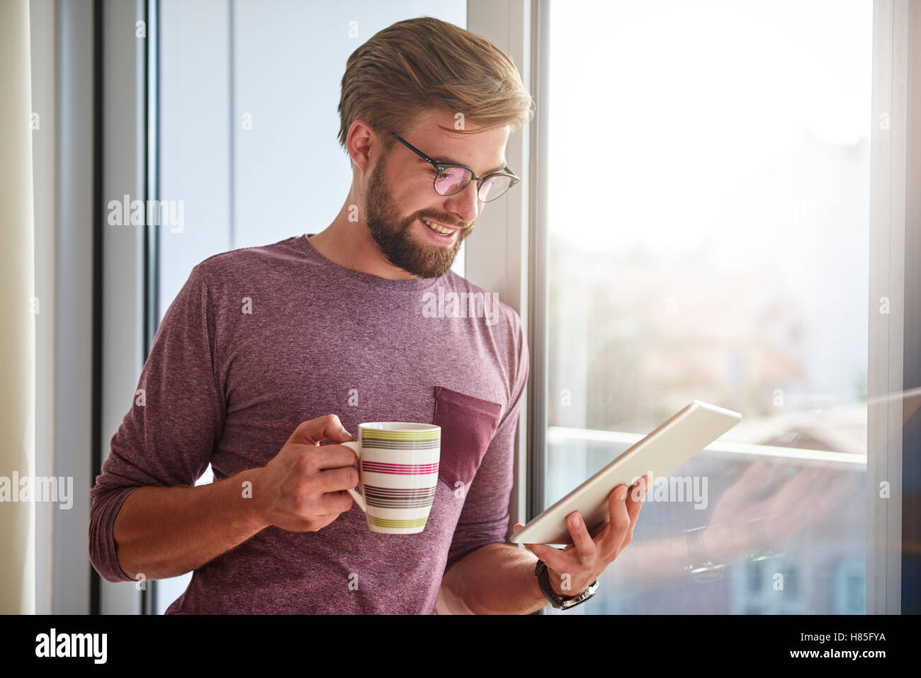 Standing man next to window with digital tablet Stock Photo - Alamy