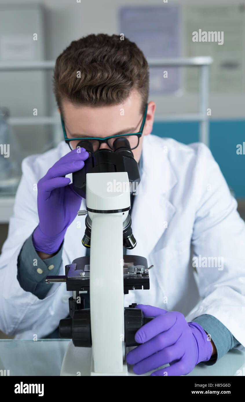 Scientist looking through a microscope in a laboratory Stock Photo - Alamy