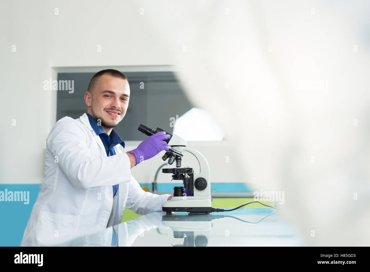 Young scientist investigating microbiological substance in microscope ...