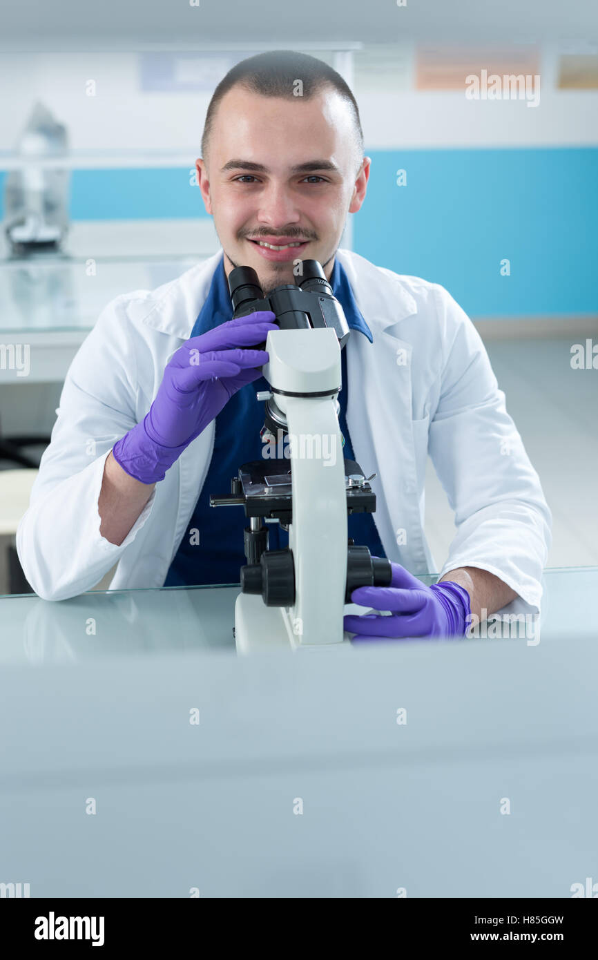 Young scientist investigating microbiological substance in microscope ...