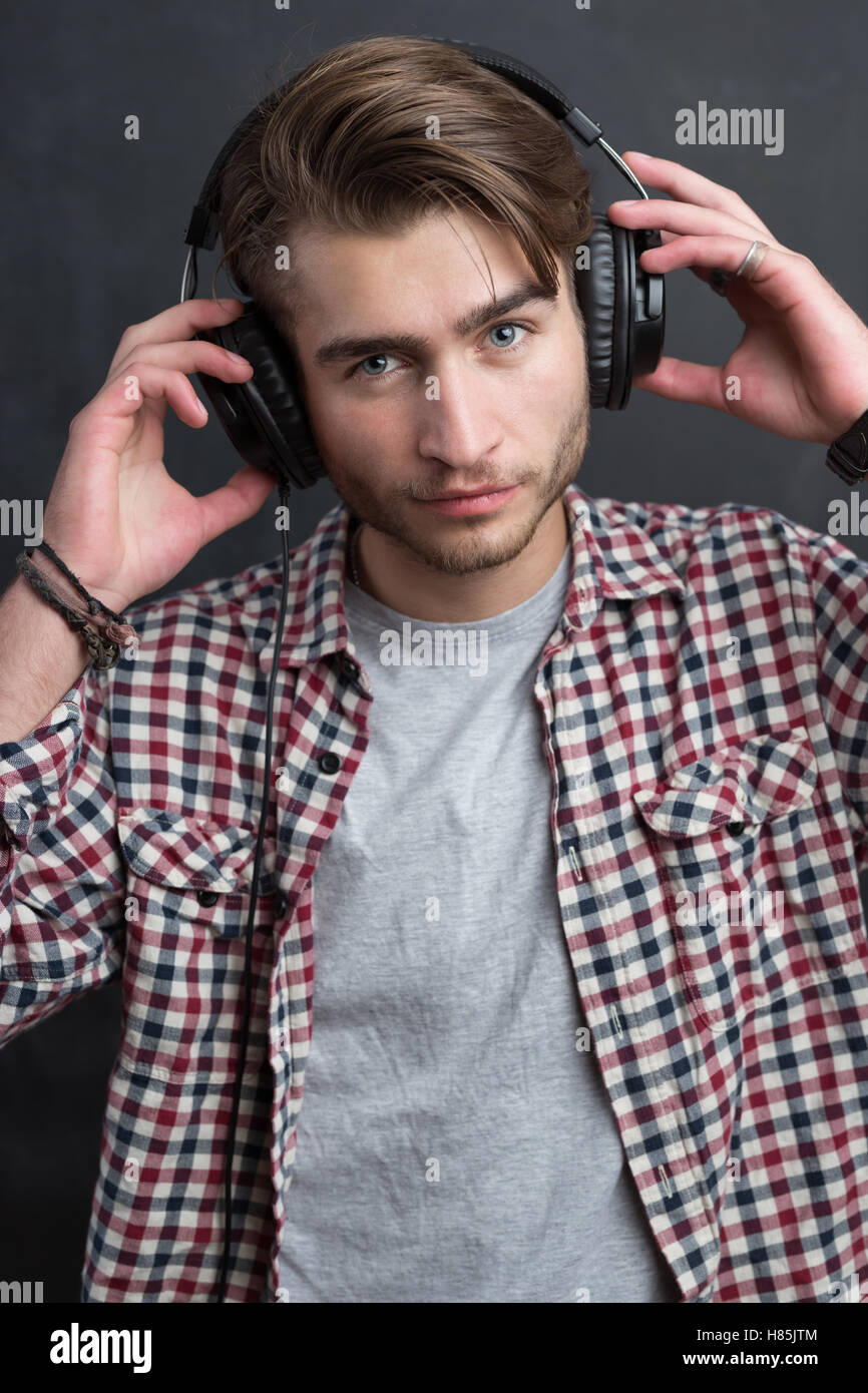 Portrait of confident young DJ with stylish haircut and headphones on ...