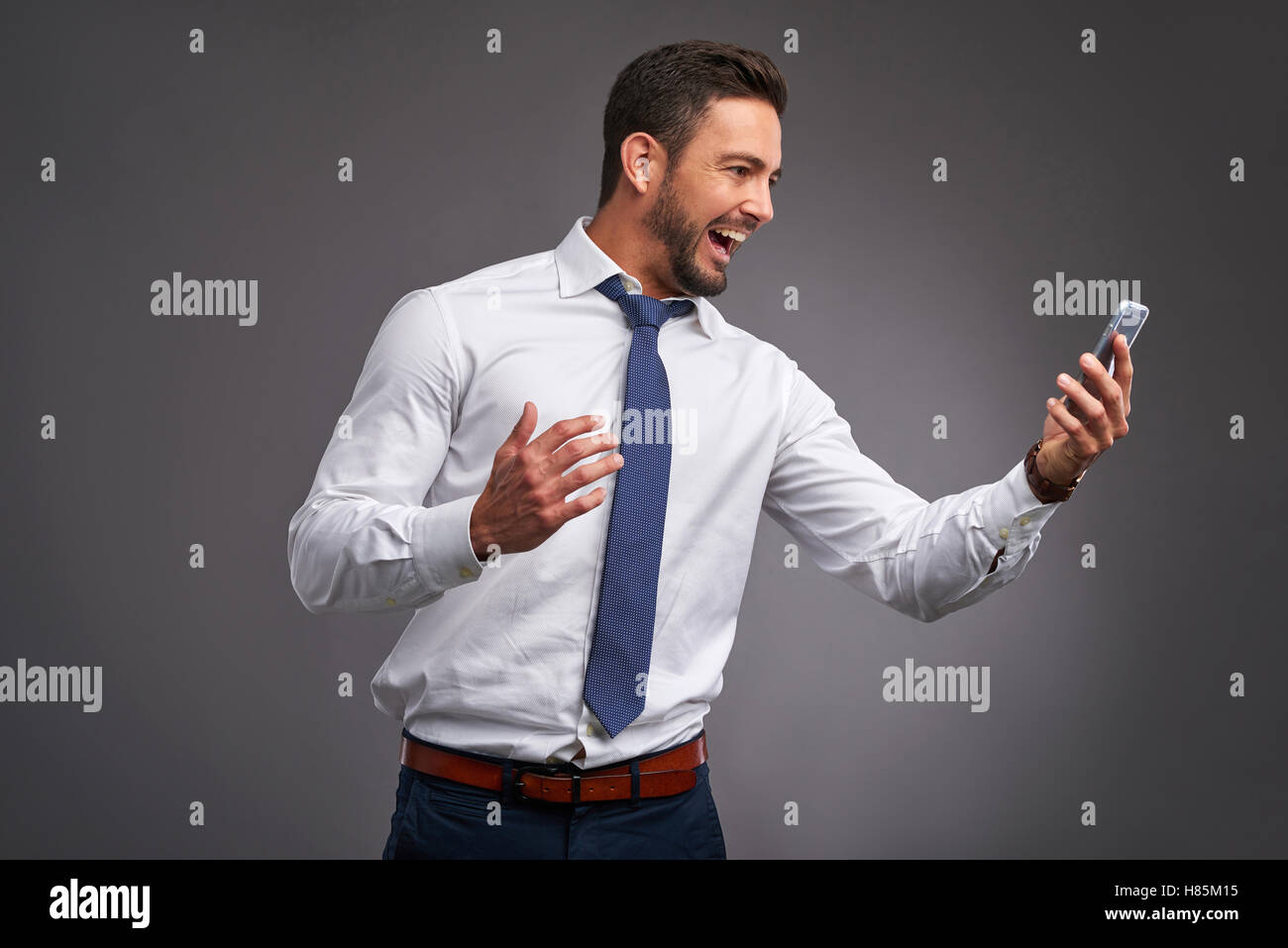 A handsome young man holding his phone and screaming to it wearing a ...