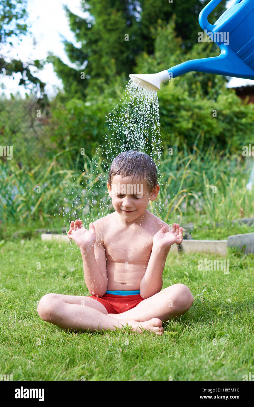 Little boy pouring water from watering can in summer day Stock Photo ...