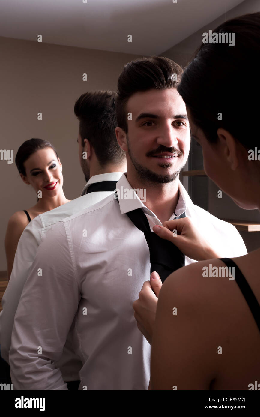 A young couple preparing to go out and getting ready and dressed in the ...