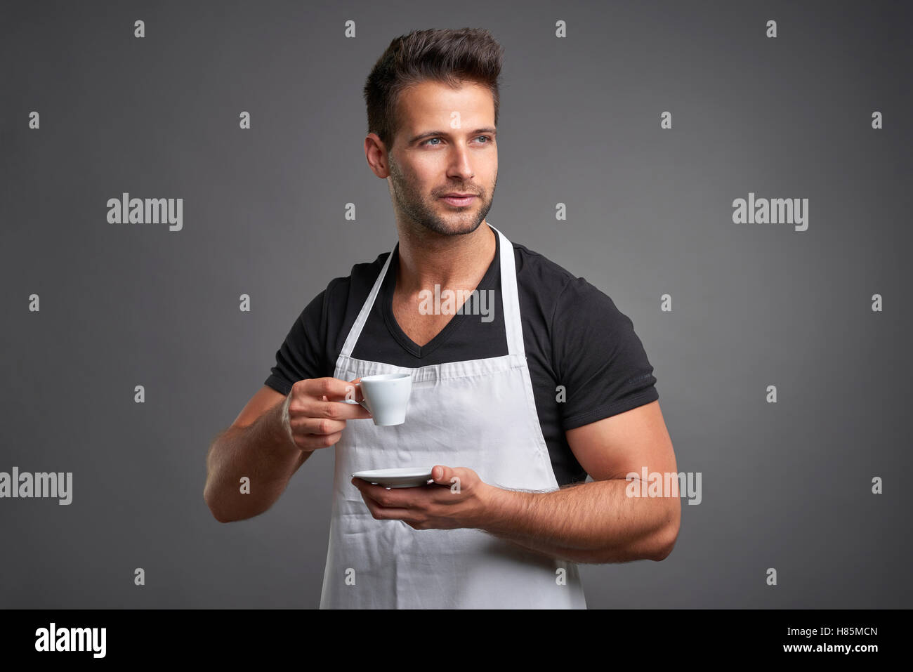 A young barista man smiling and enjoying a cup of coffee Stock Photo ...