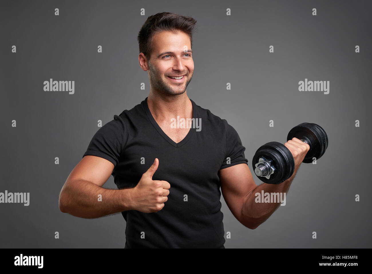 A handsome young man lifting weight smiling and showing thumbs up Stock ...