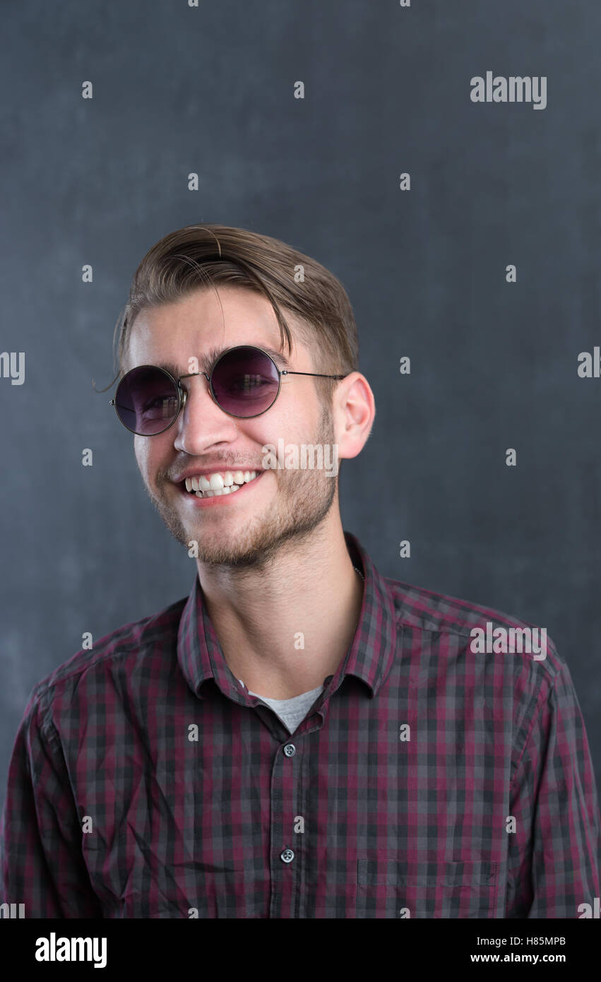 Portrait of a relaxed young man with checkered shirt and sunglasses ...