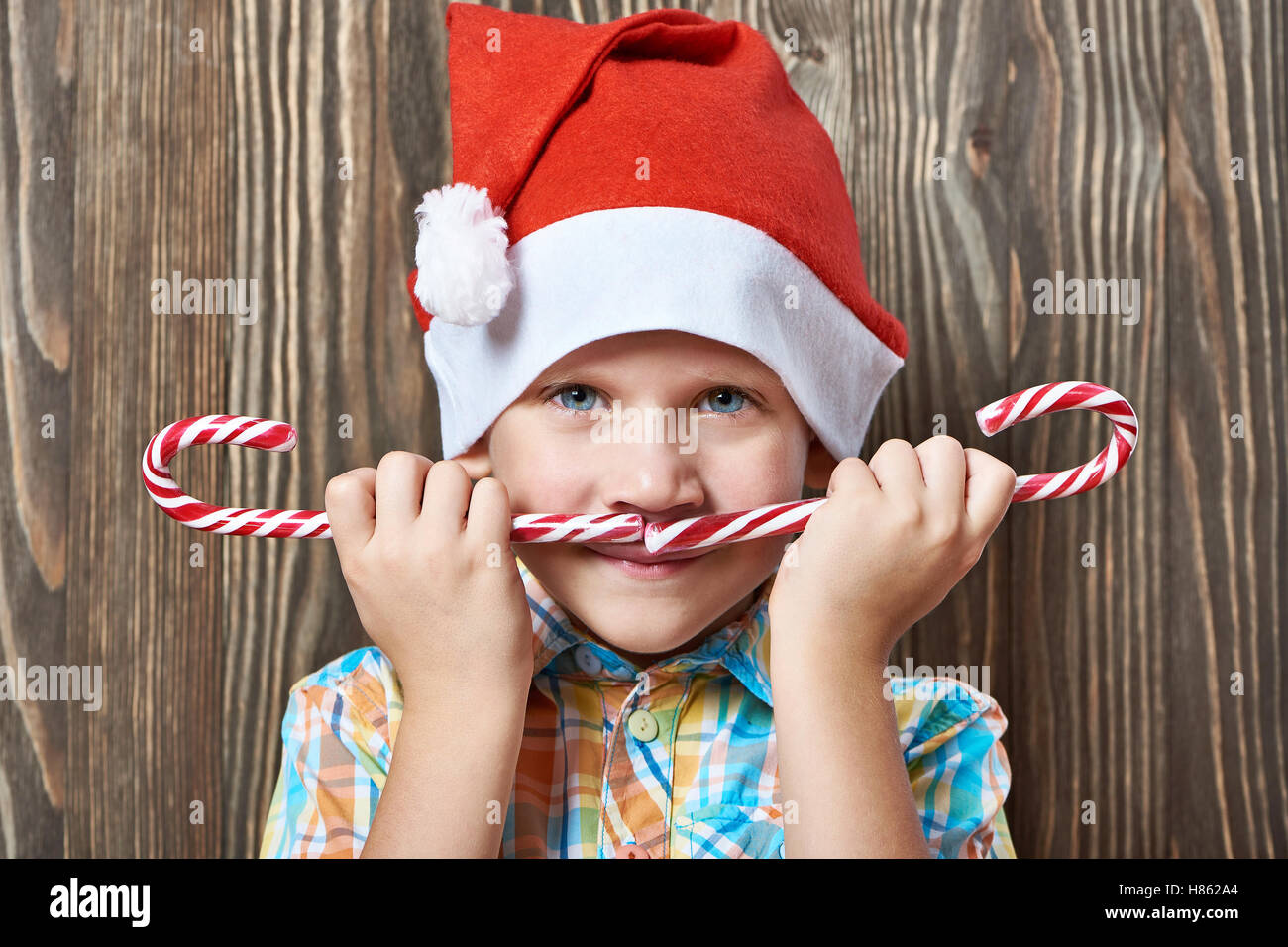 Little boy in a New Year's red cap with two Christmas candy canes Stock ...
