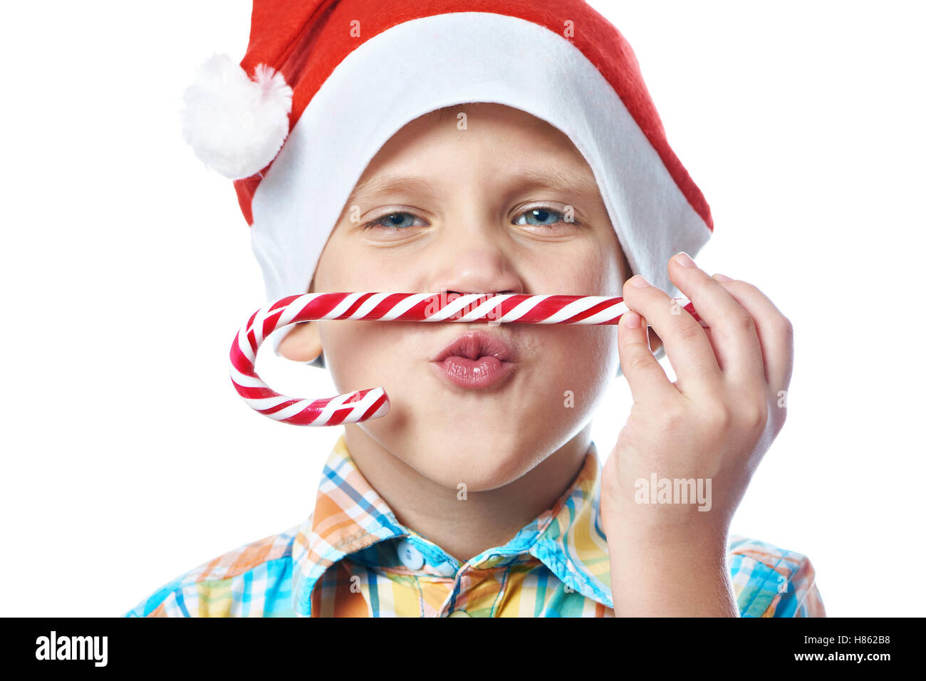 Little boy in a New Year's red cap with Christmas candy cane isolated ...