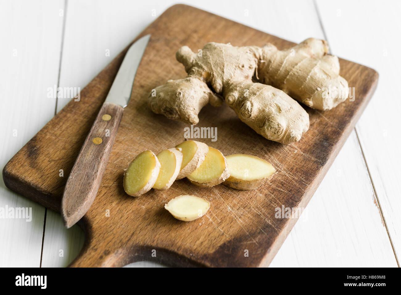 Close-up of ginger root sliced on cutting board with old rustic knife ...