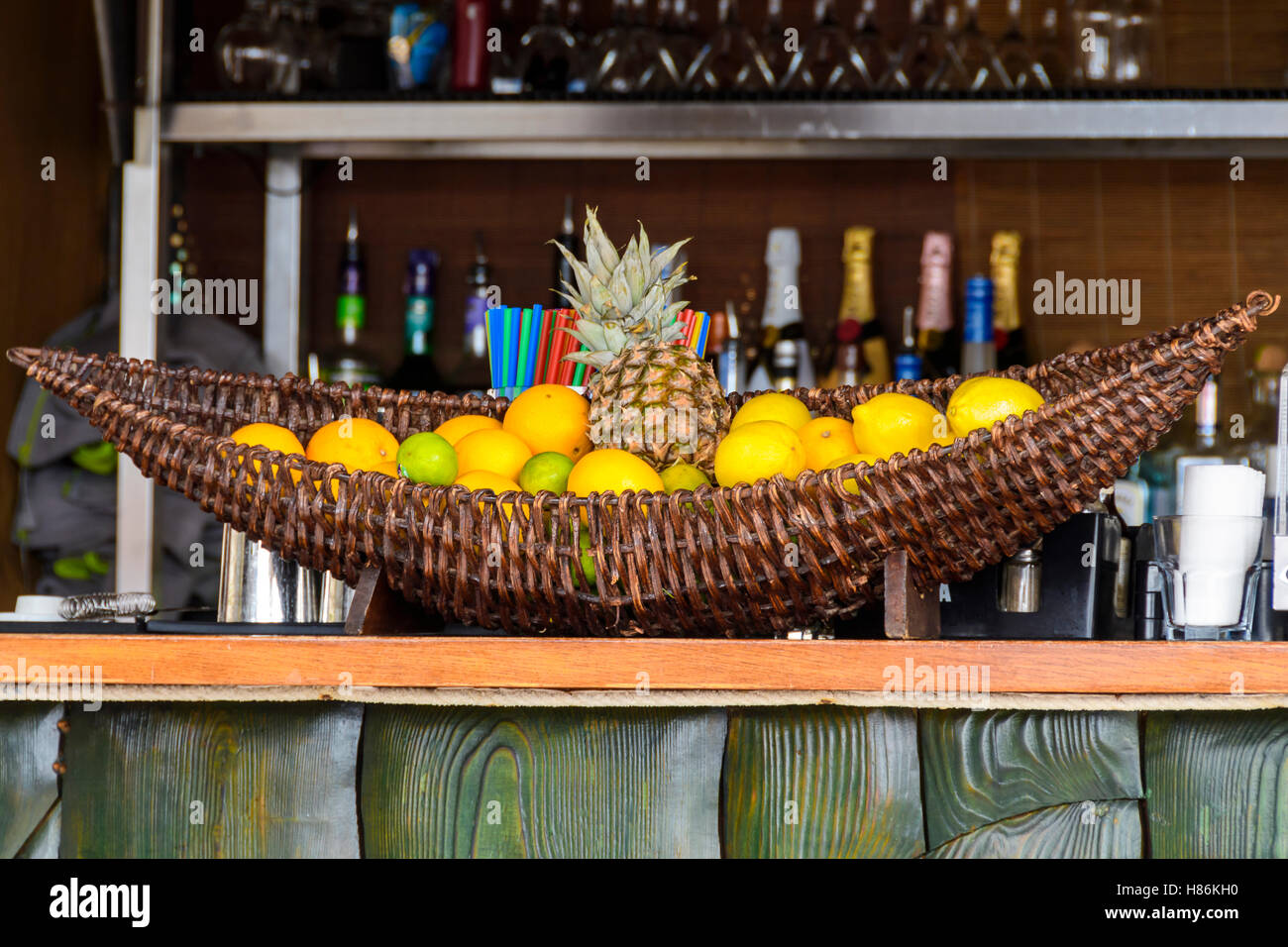 Bar counter with fruits in basket and shelfs with bottles in background ...