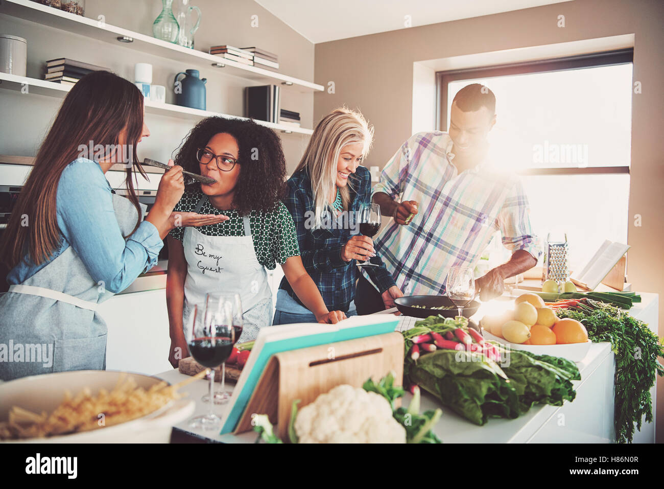 Good friends tasting food at table full of vegetables and pasta ready ...