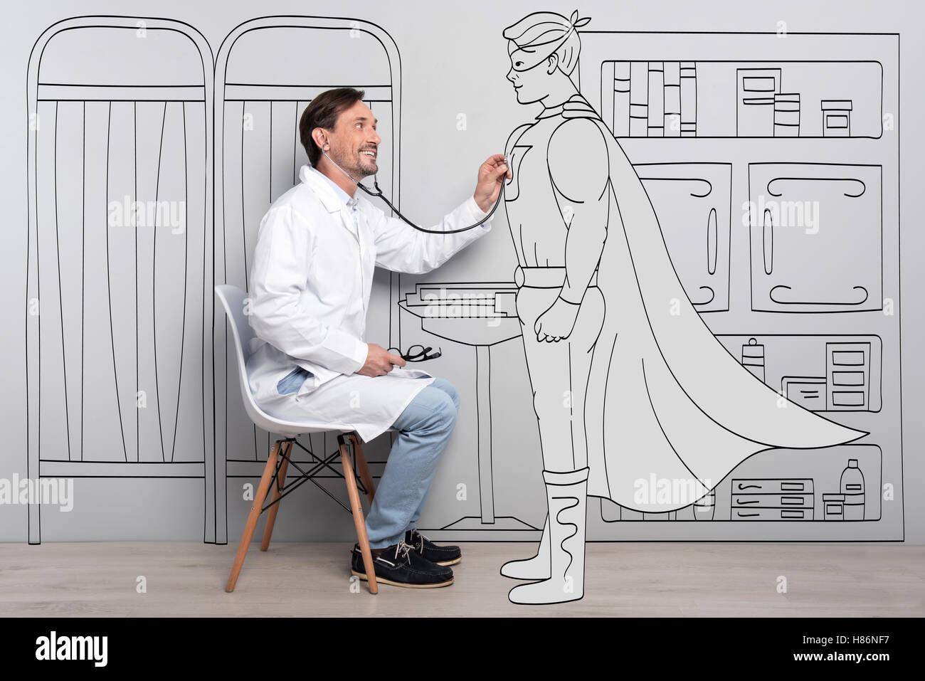 Happy smiling doctor examining superman Stock Photo - Alamy