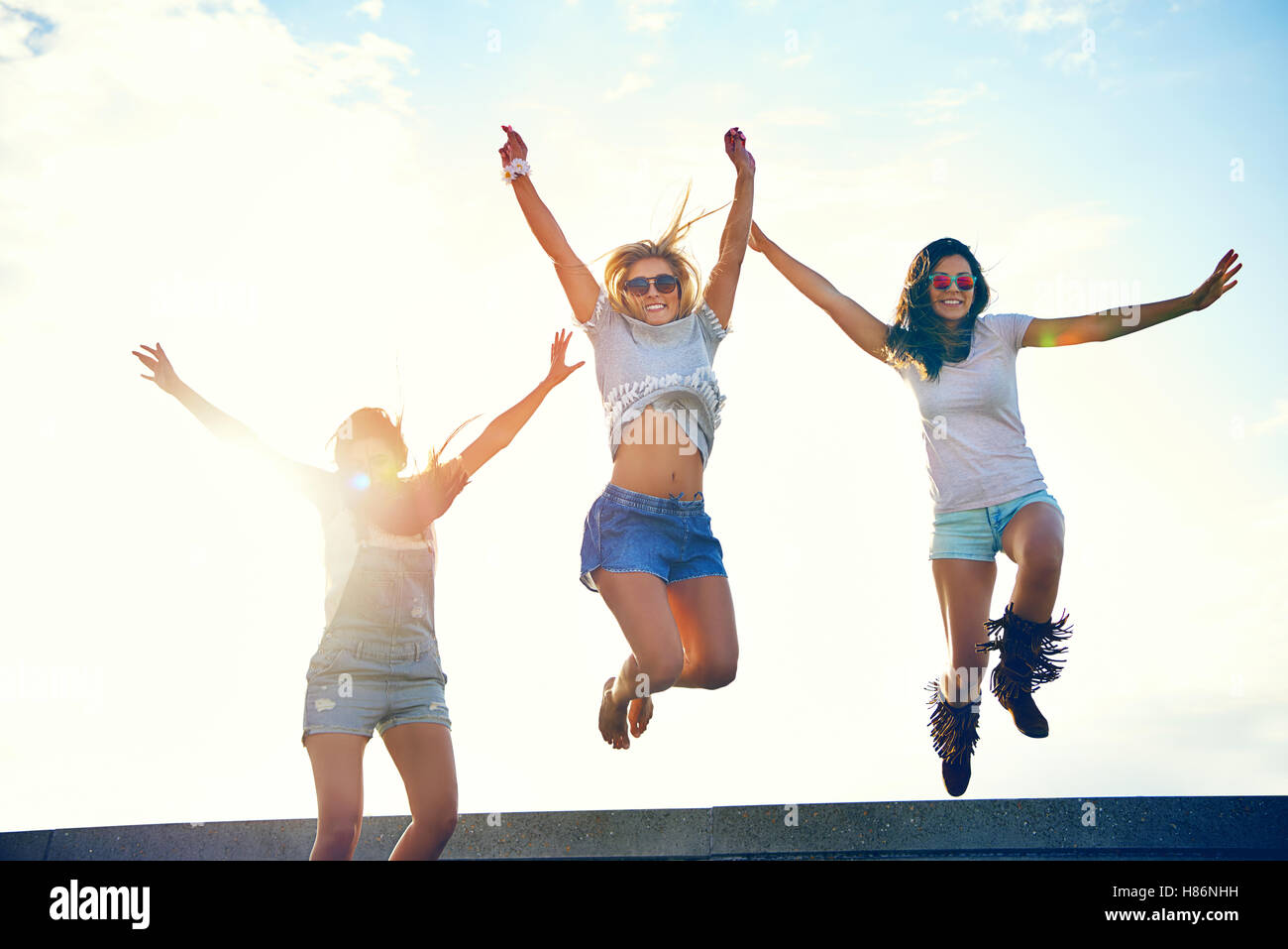Three joyful young women leaping in the air celebrating the freedom of ...
