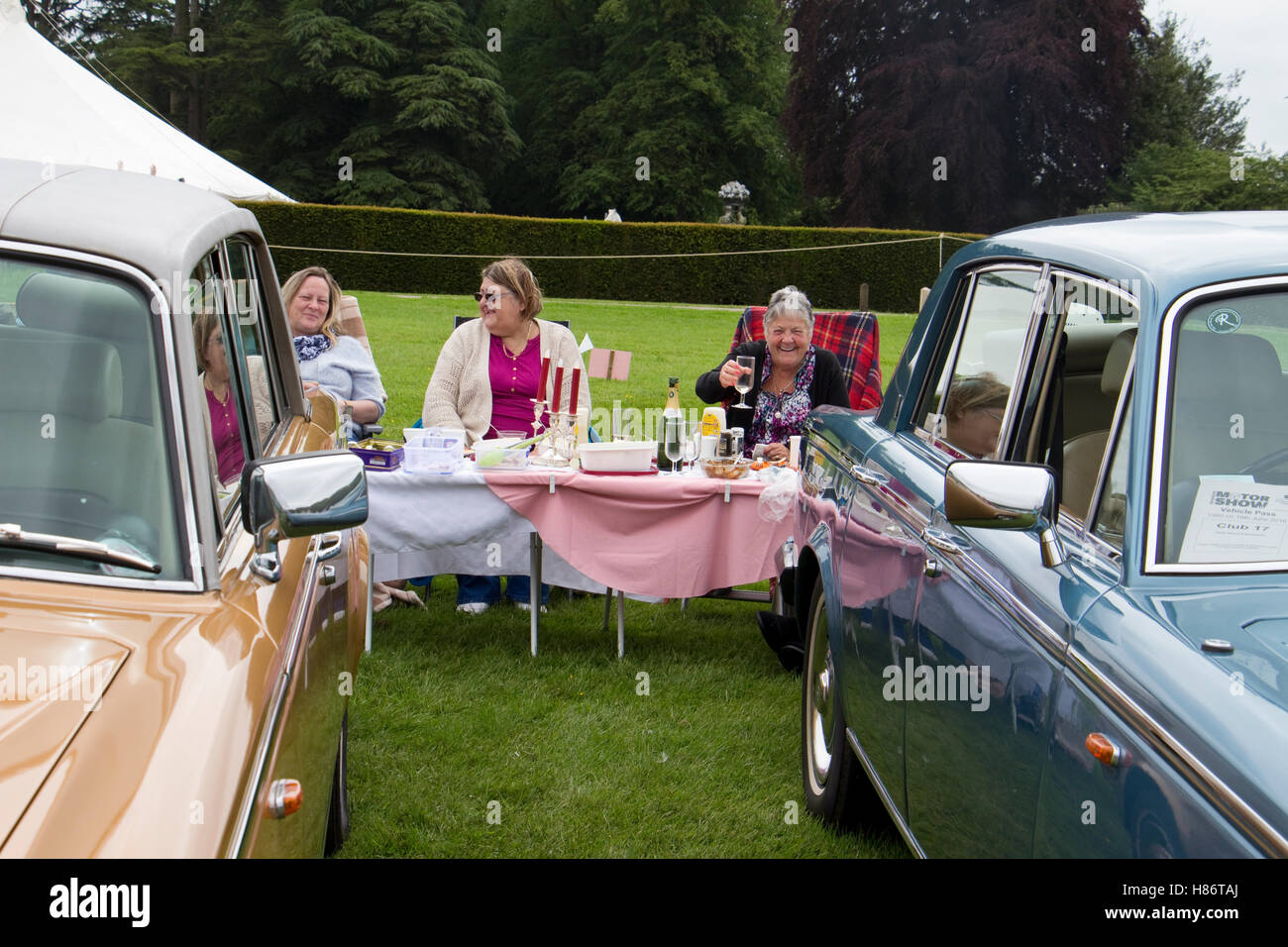 Three ladies having tea at a vintage motor show between two classic ...