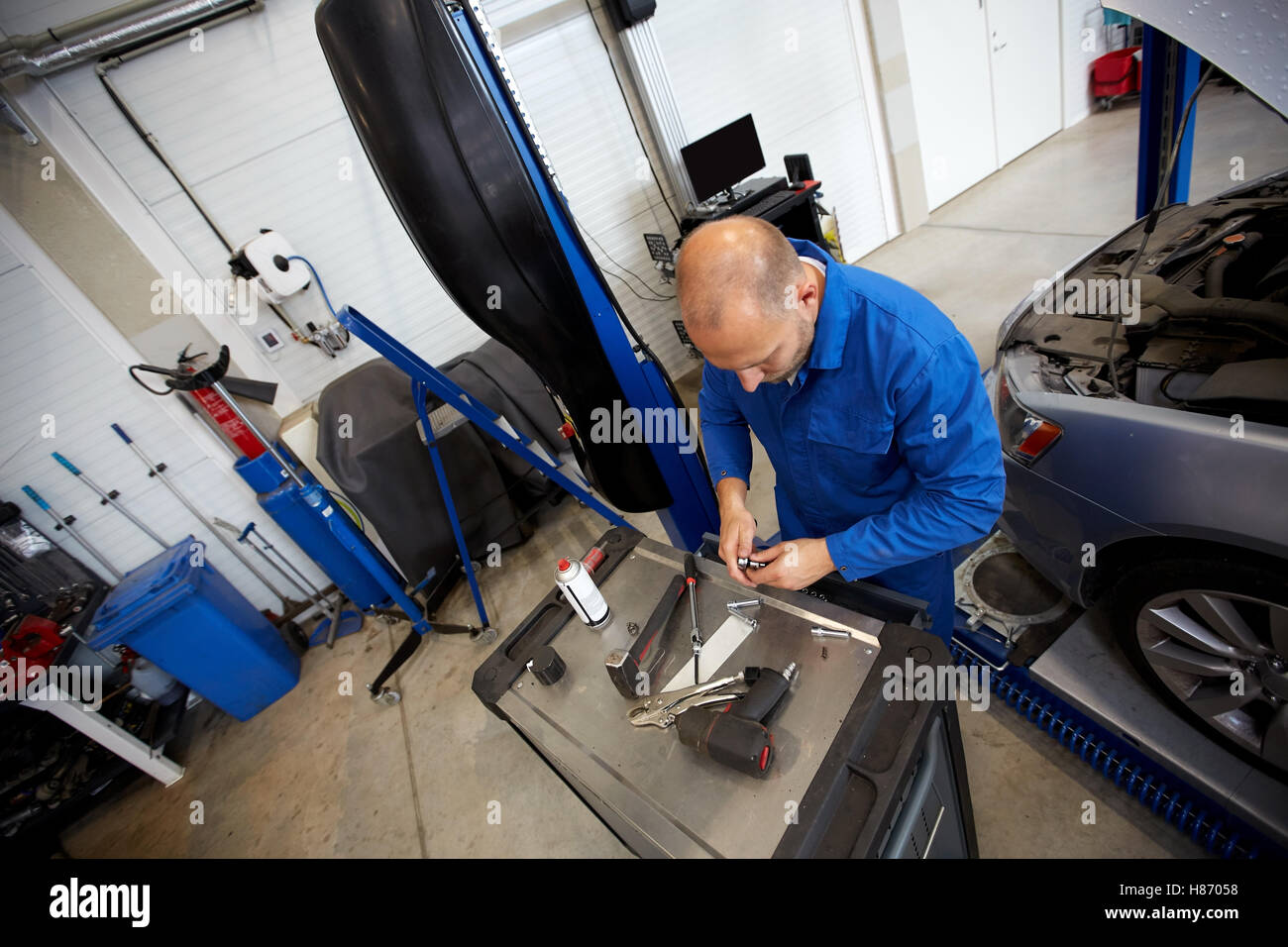 mechanic man with wrench repairing car at workshop Stock Photo - Alamy