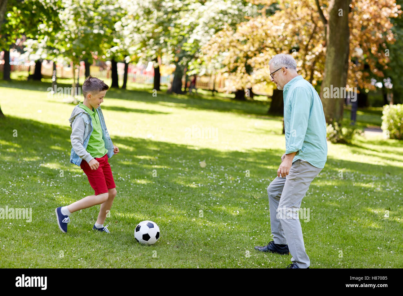 old man and boy playing football at summer park Stock Photo - Alamy