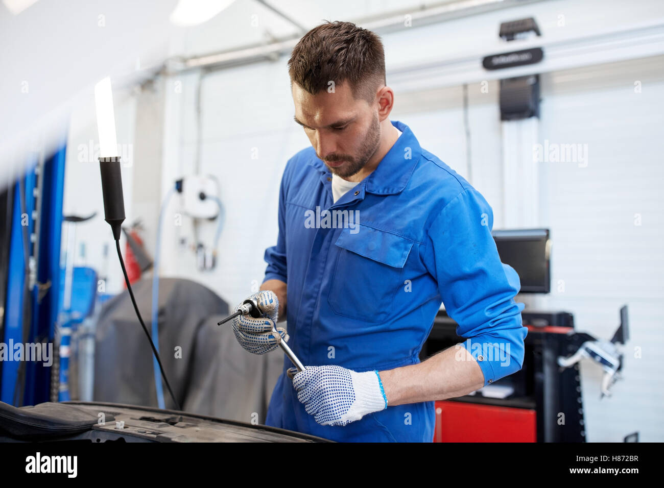 mechanic man with wrench repairing car at workshop Stock Photo - Alamy
