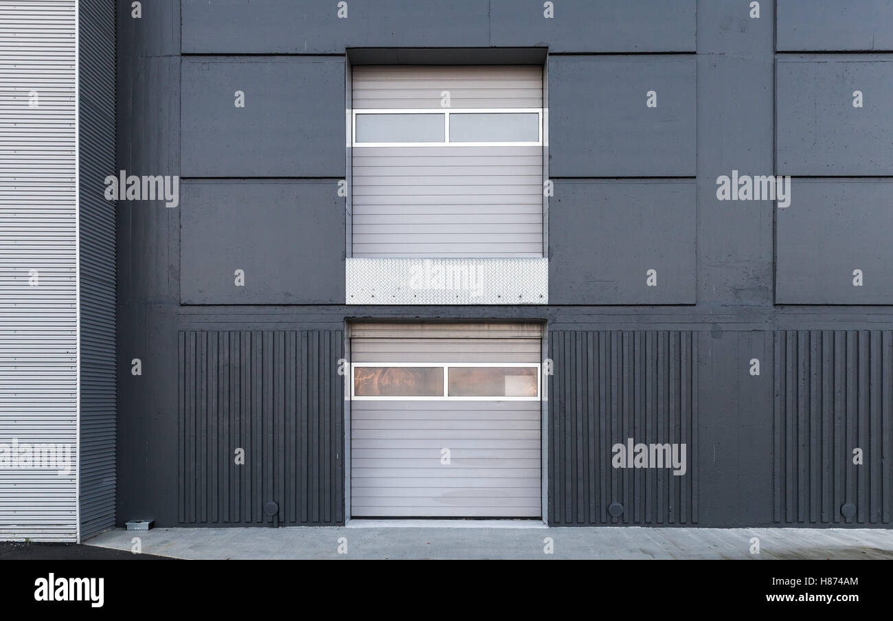 Two level closed gates in gray metal warehouse wall, flat background ...