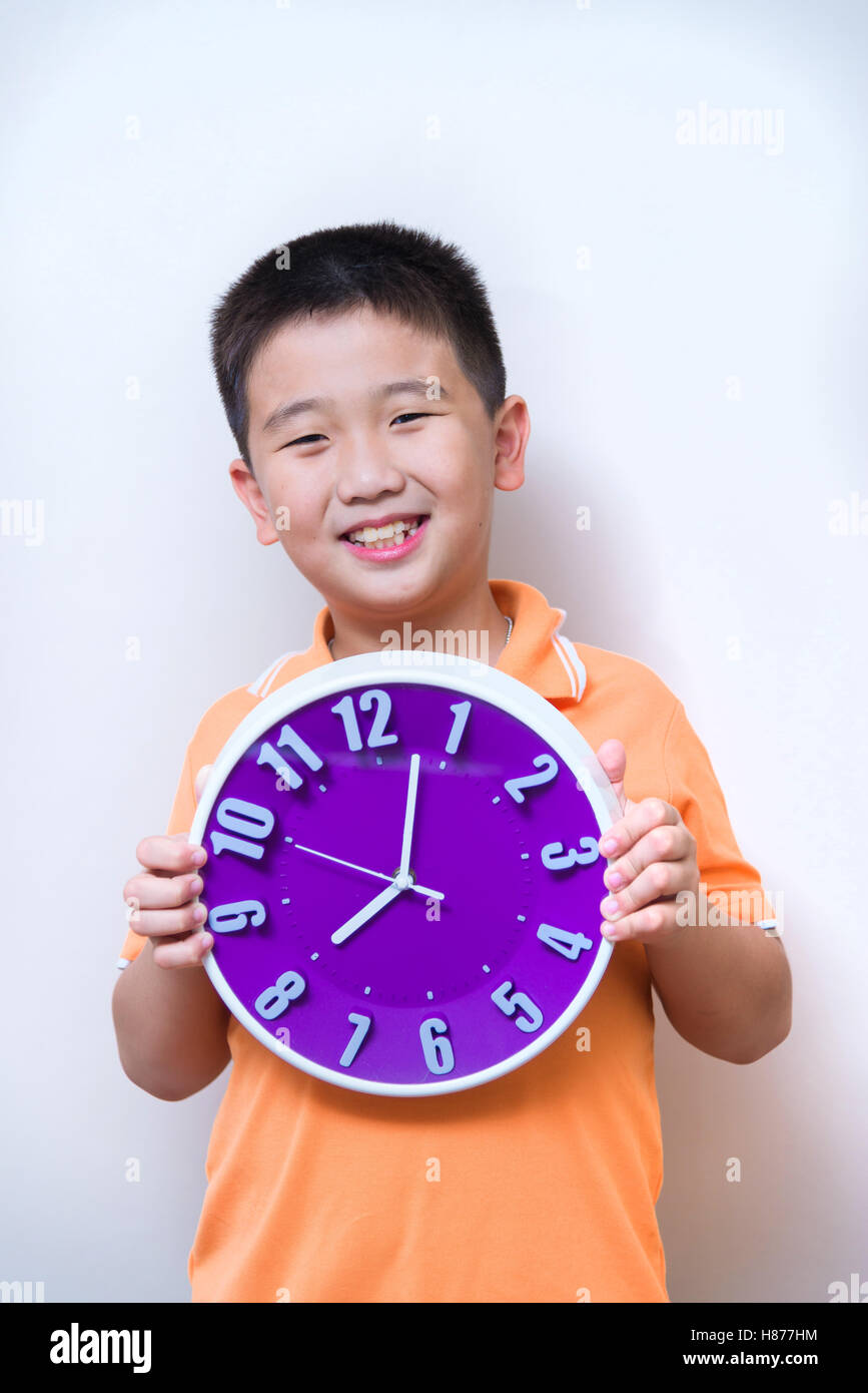 Asian boy showing and holding purple or violet clock in studio shot, on ...