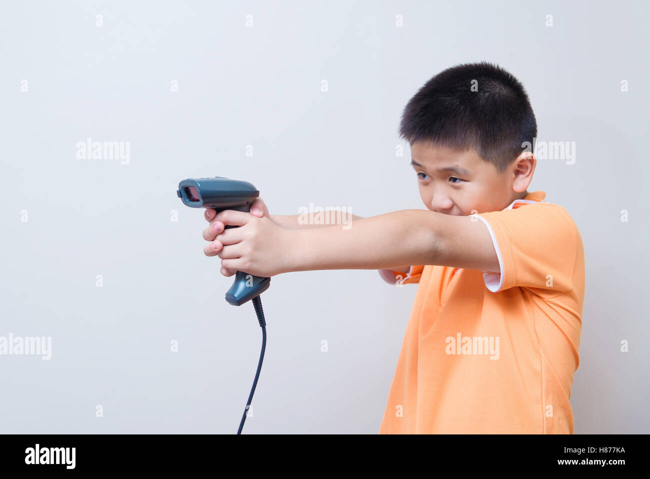 Asian boy aim a fake gun made with barcode scanner, studio shot, on ...