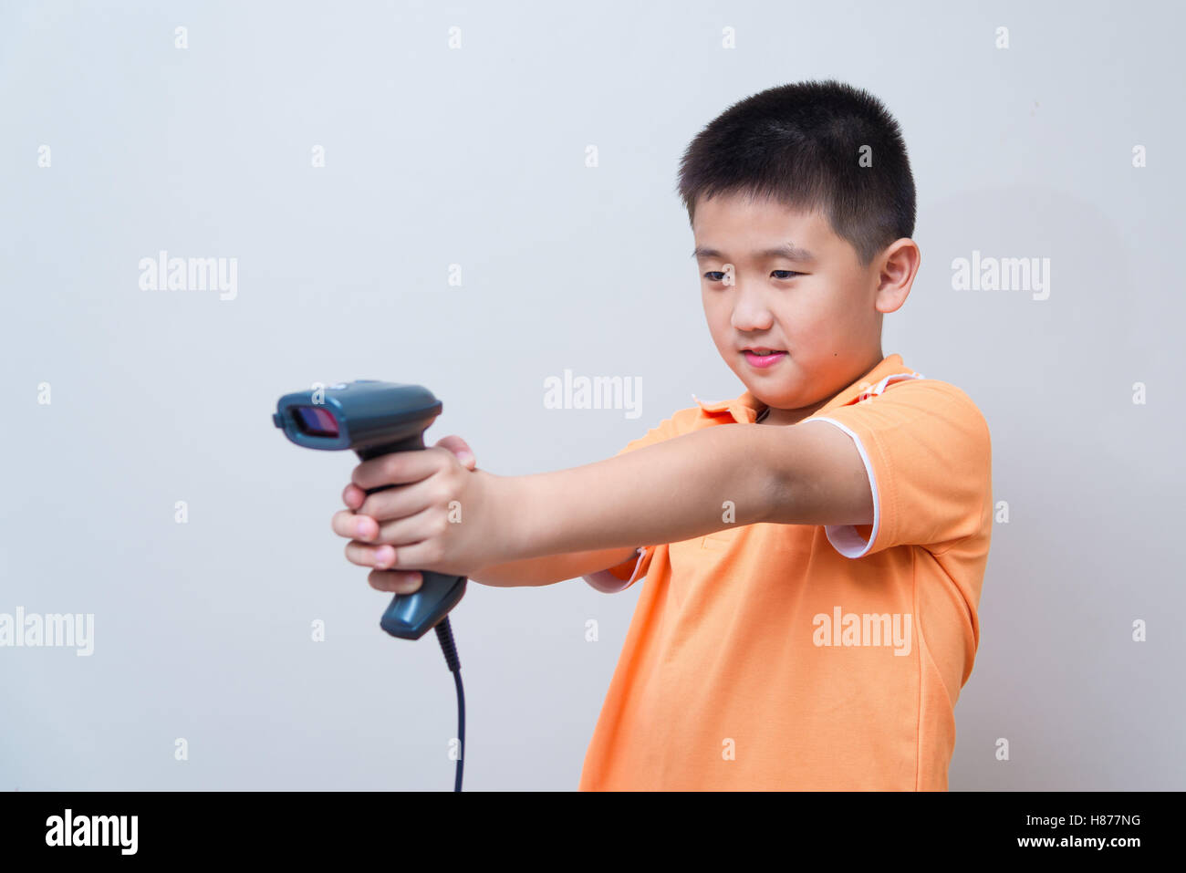 Asian boy aim a fake gun made with barcode scanner, studio shot, on ...