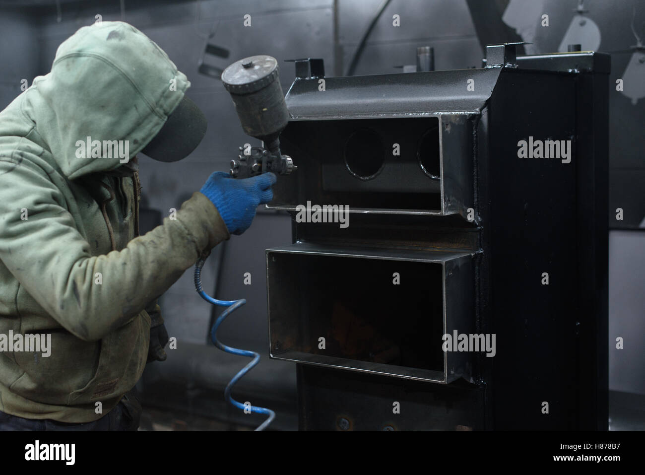 Man paints solid fuel boiler in black color Stock Photo - Alamy