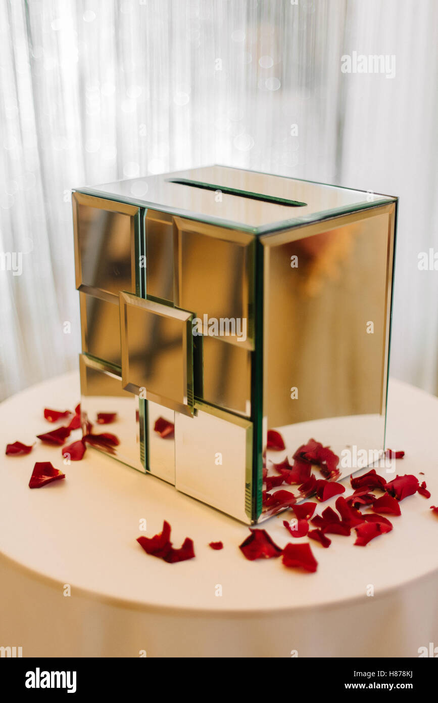 Original glass box stands on the table with red petals Stock Photo - Alamy