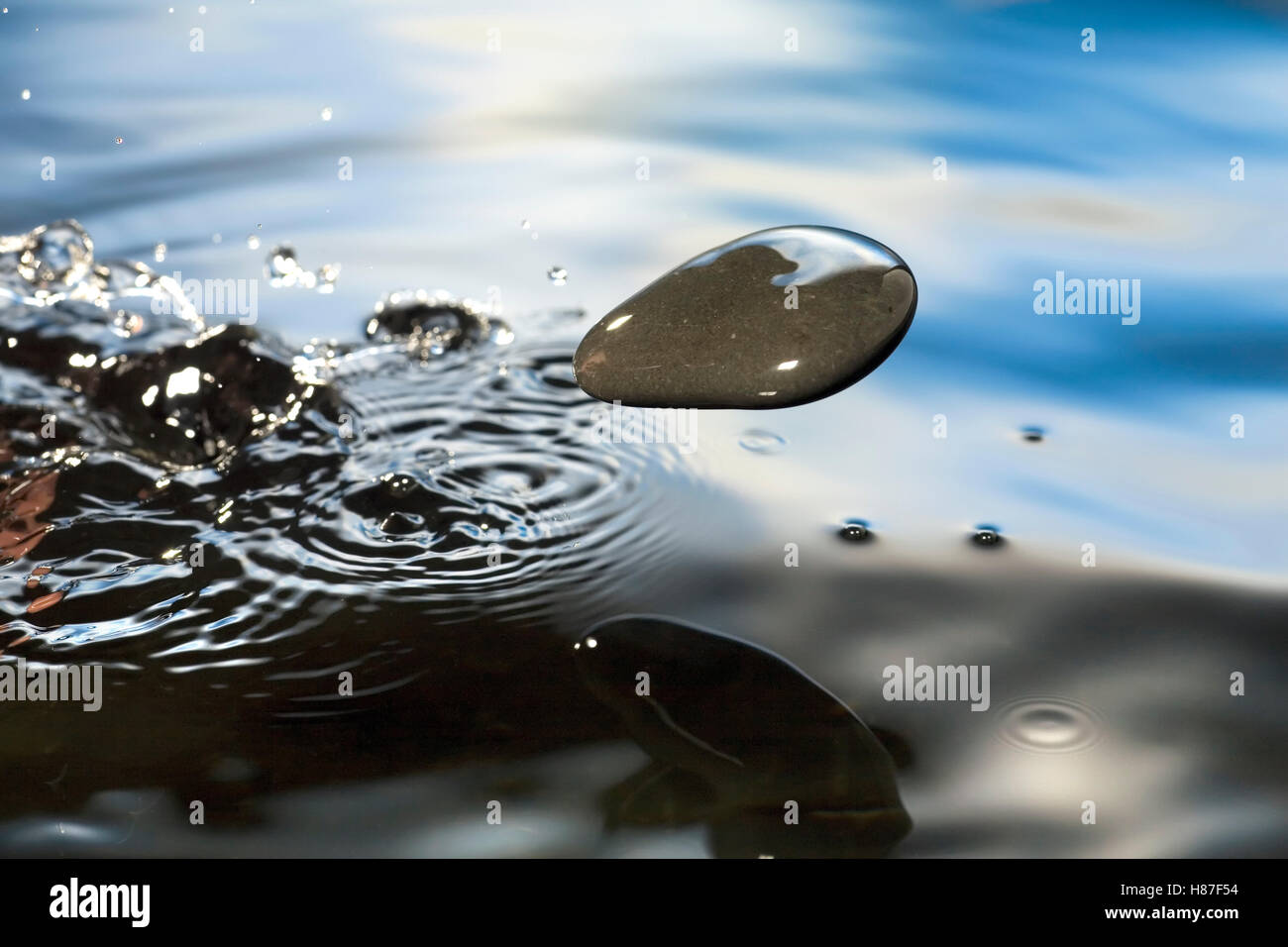 A rock skipping across the water's surface Stock Photo - Alamy