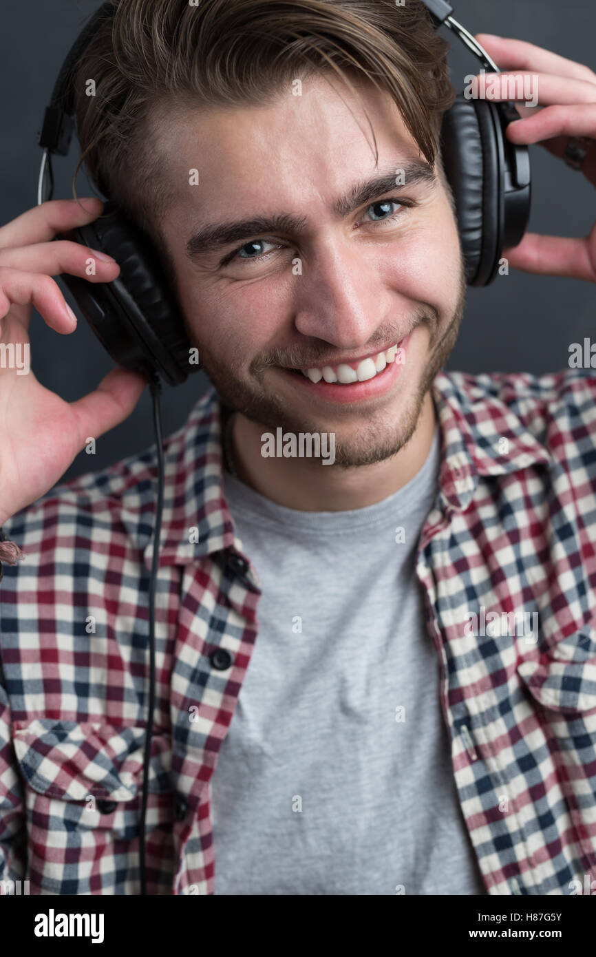 Portrait of confident young DJ with stylish haircut and headphones on ...