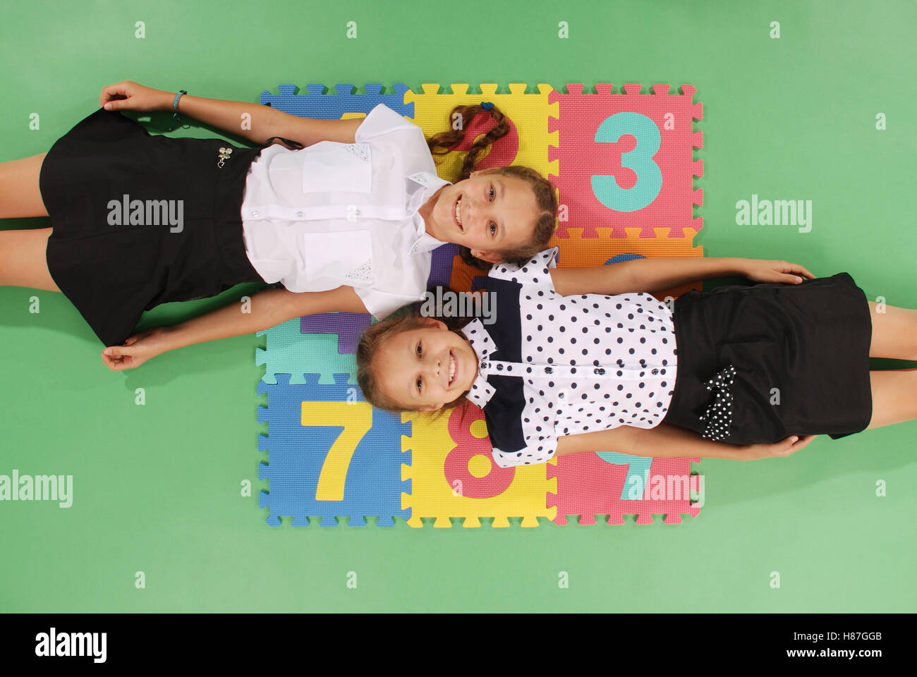 Two girls on rug with numbers one, two, three, four, five, six, seven ...